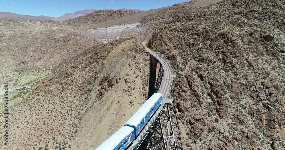 Aerial flying over train while it drives through old metal bridge at ...