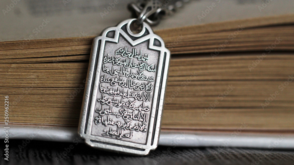 Muslim talisman with prayer on a chain and book Stock Photo | Adobe Stock
