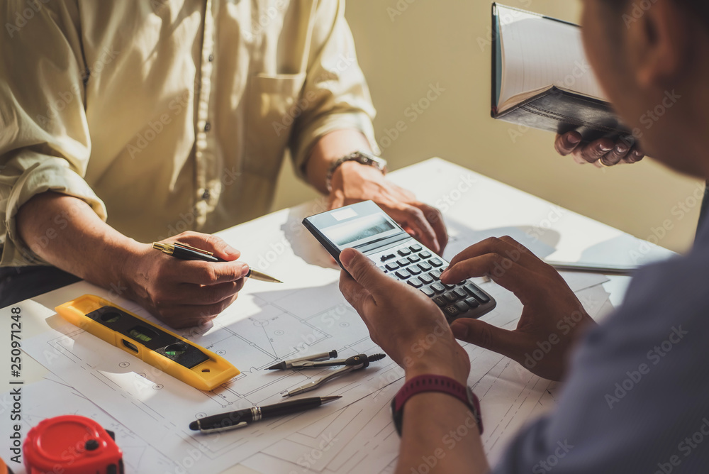 Group of architects discussing and useing calculator about calculate ...