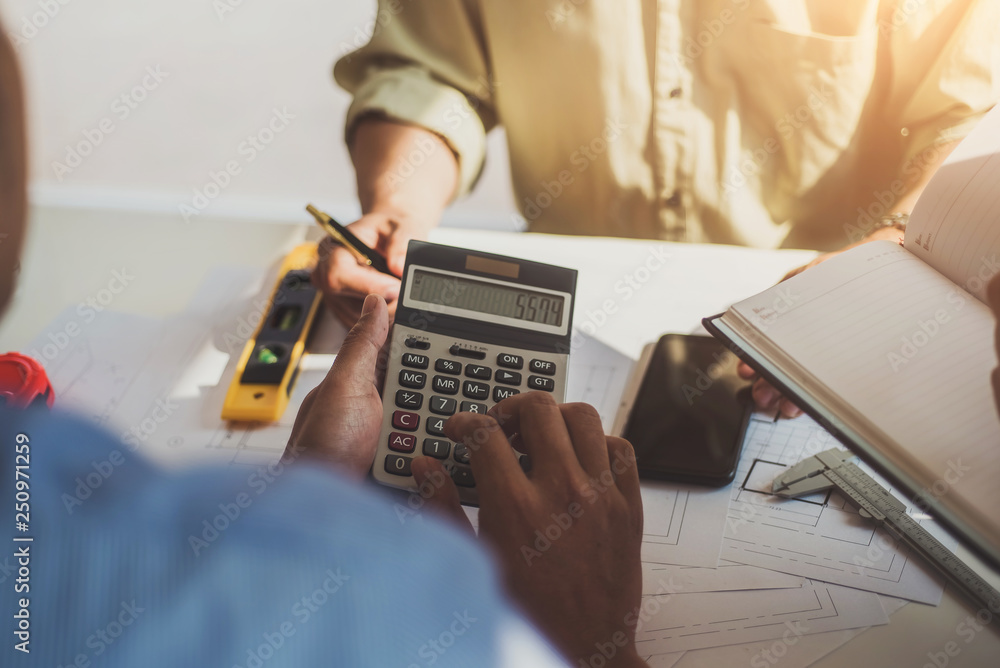 Group of architects discussing and useing calculator about calculate ...