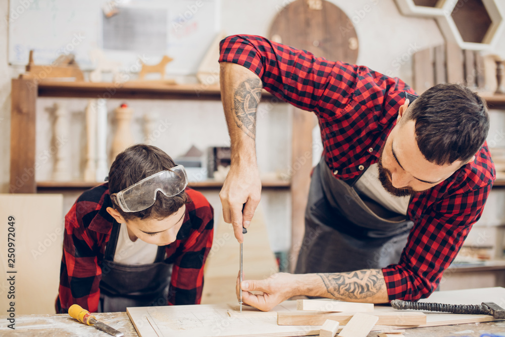 Father and son in workshop tinkering wooden toy. Dad teaching little ...