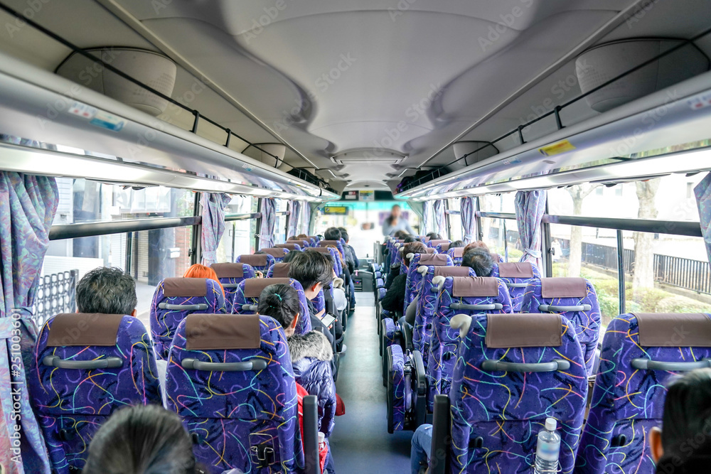 People on the bus were sitting listen to tour guide who standing at ...