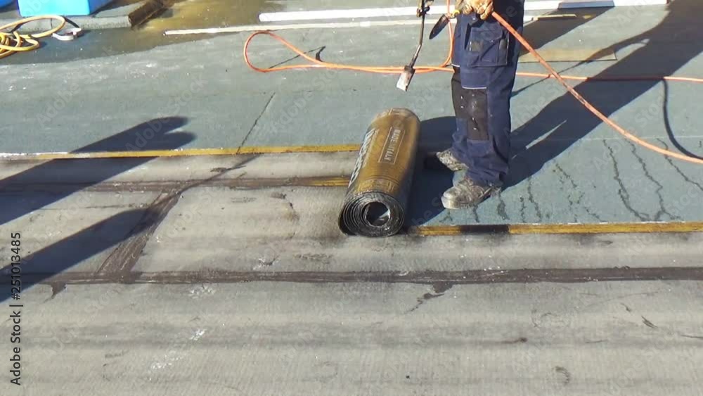 Worker performs sealing overlapping bitumen sheets on the flat roof of ...