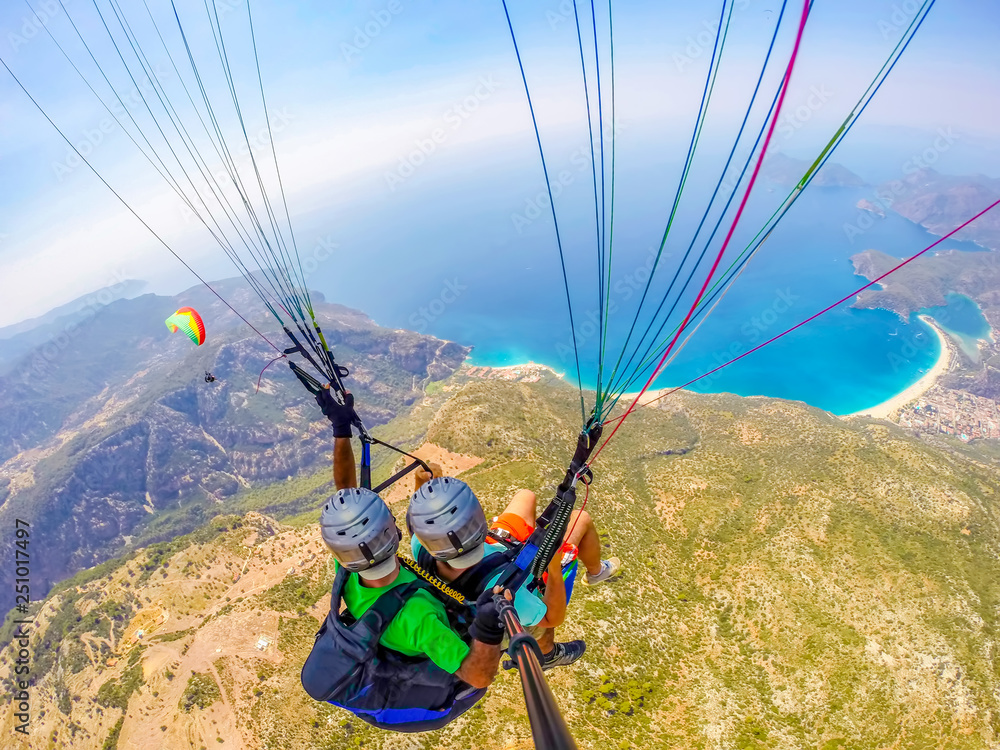 Paragliding in the sky. Paraglider tandem flying over the sea with blue ...