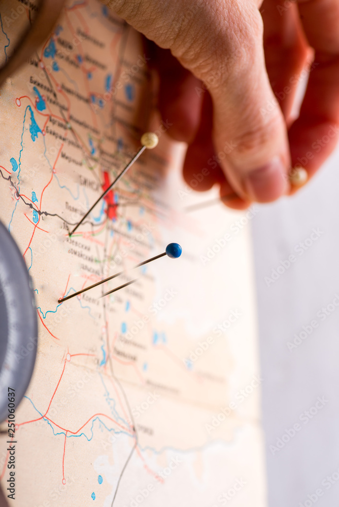hand marks places on the map with pins. Сompass on a leather belt on ...
