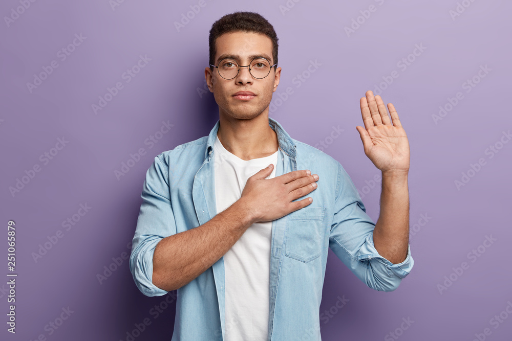 Honest serious hipster guy swears to do something, keeps hand on chest ...