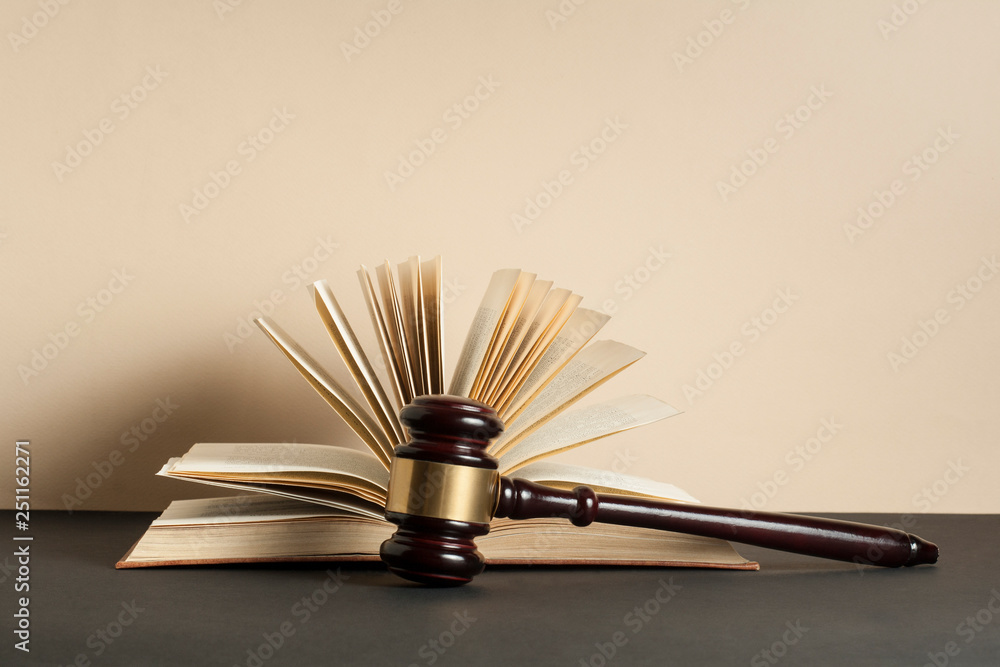 Law concept. Open book with wooden judge gavel on table in a courtroom ...