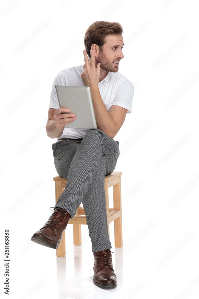 confused and curious man sitting, holds a tablet and gestures Stock ...