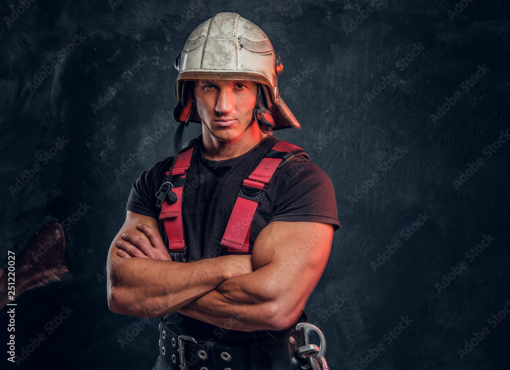 Confident firefighter wearing a fire helmet posing with crossed arms ...