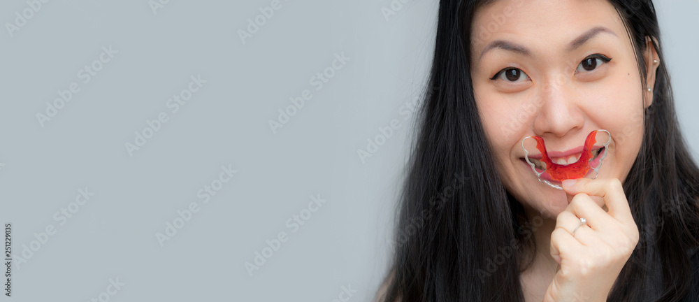 Portrait of beautiful Asian patient woman holding orthodontic retainers ...