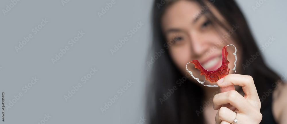 Portrait of beautiful Asian patient woman holding orthodontic retainers ...