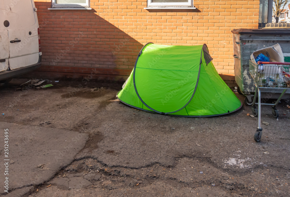 Small green tent used by a homeless person and set up in an alleyway ...