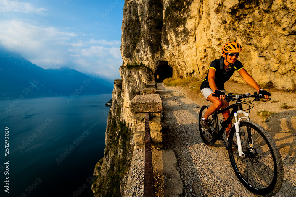 Cycling woman riding on bikes at sunrise mountains and Garda lake ...