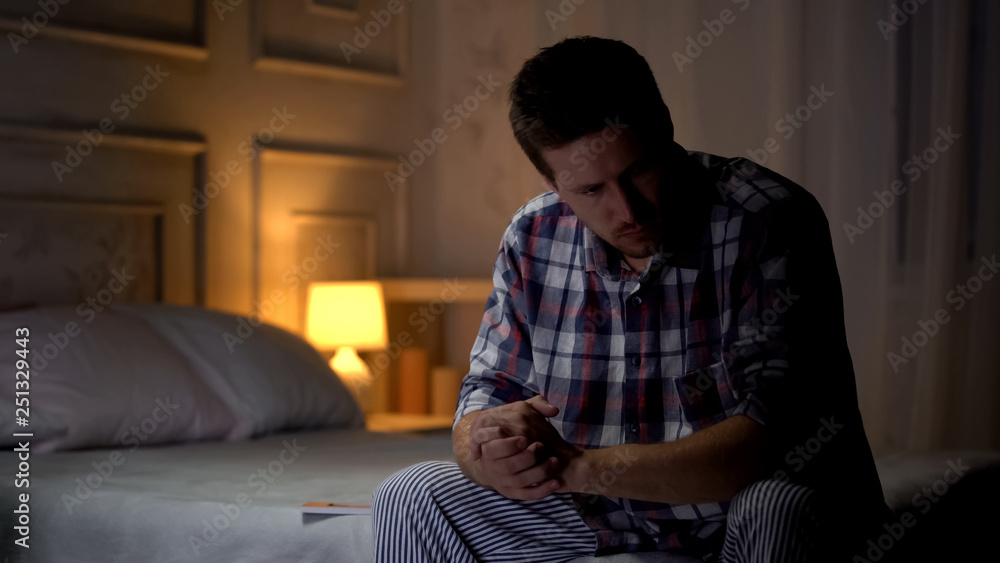 Lonely sad man sitting on bed, experiencing painful wife loss, grief ...