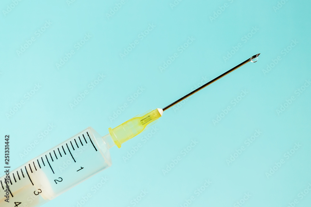 Close up of a medical syringe with a drop of drug or medicine at the ...