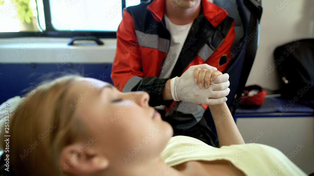 Paramedic holding patient hand in ambulance, medical care and moral ...