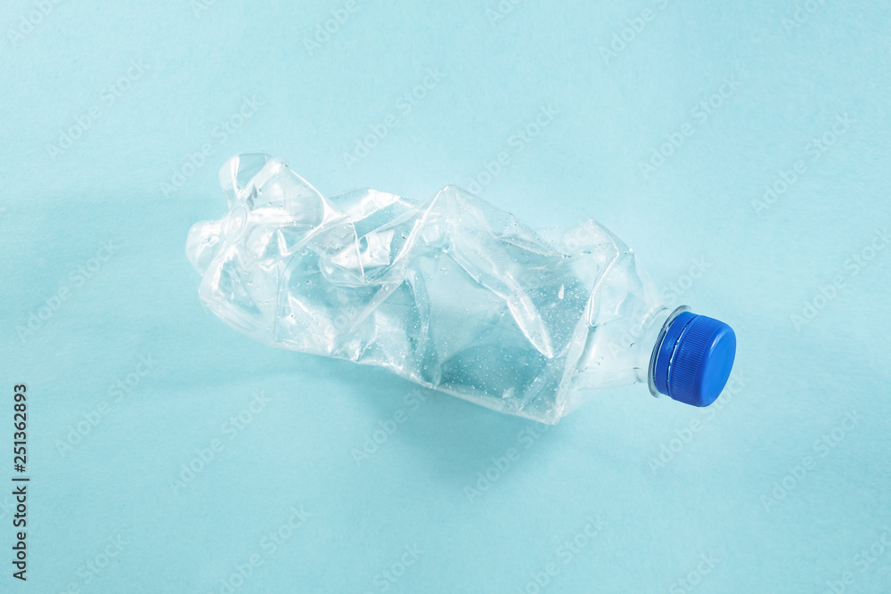 Plastic waste concept: discarded crumpled water bottle in blue ...