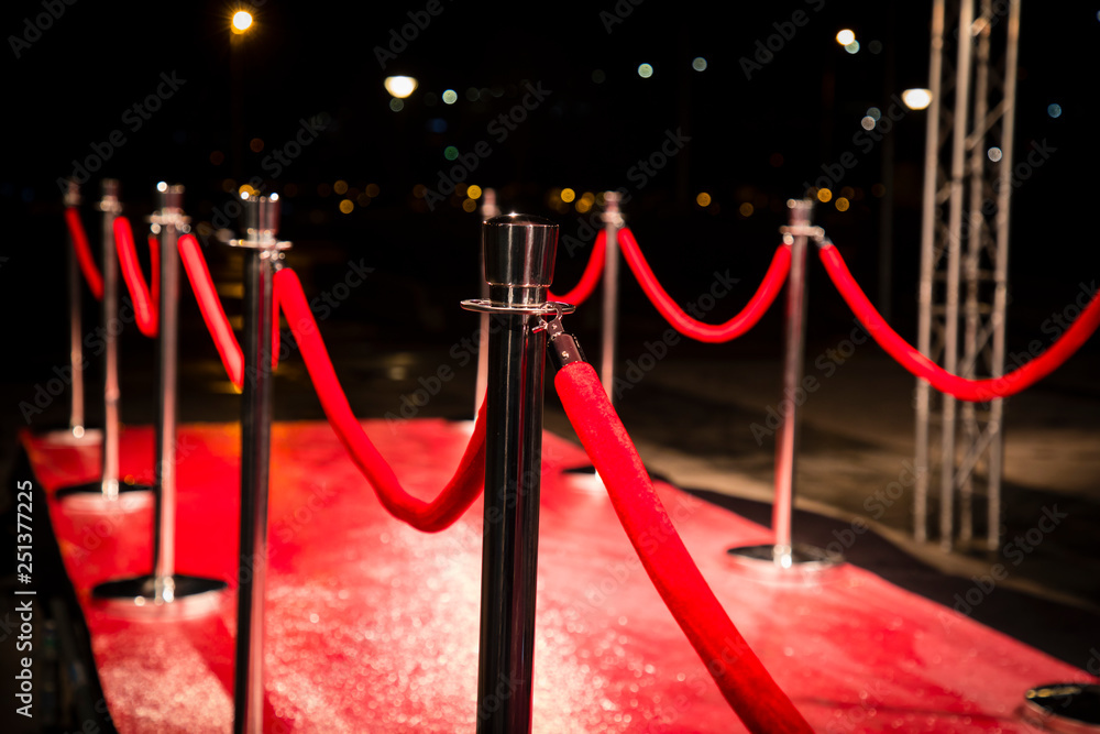 Red carpet with barriers, velvet ropes and lights in the background ...