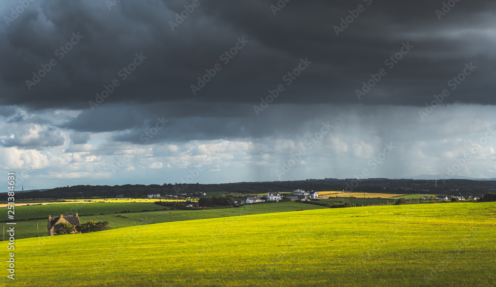 Grey rainy sky above the green meadow. Northern Ireland landscape ...