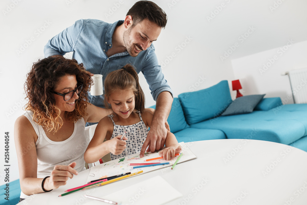 Parents teach they young daughter to draw.They sitting in living room ...