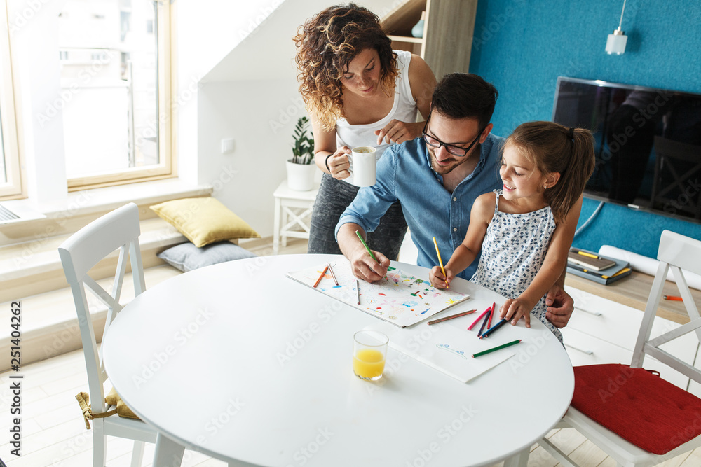 Parents teach they young daughter to draw.They sitting in living room ...