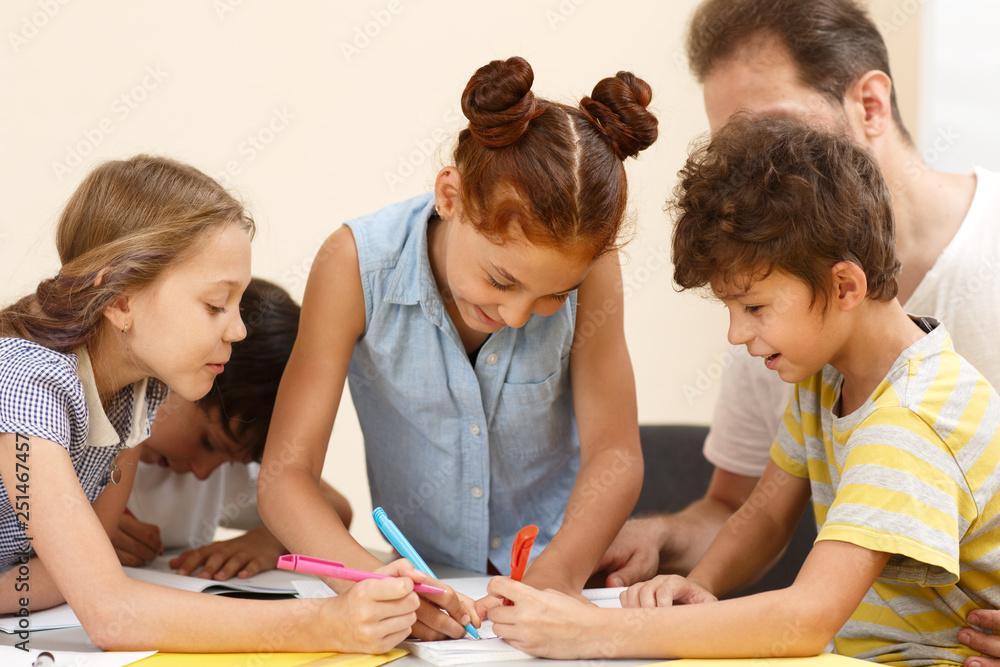 Group of little cheerful students working in team on lesson in ...