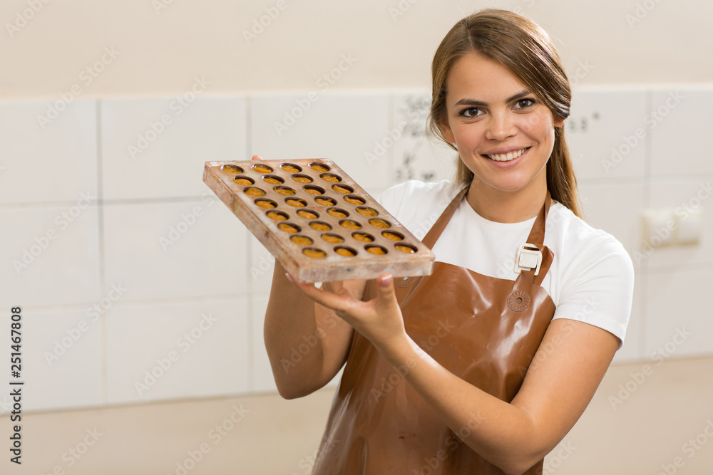 Beautiful female pastry cook wearing uniform showing baking forms and ...