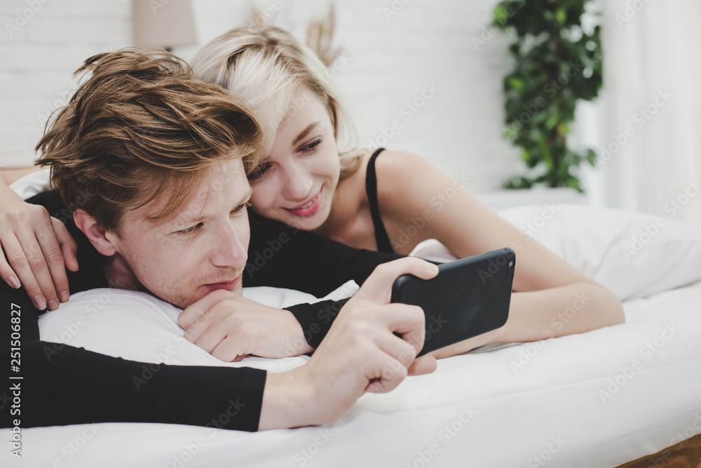 Handsome boyfriend holding smart phone and watching movie with his ...