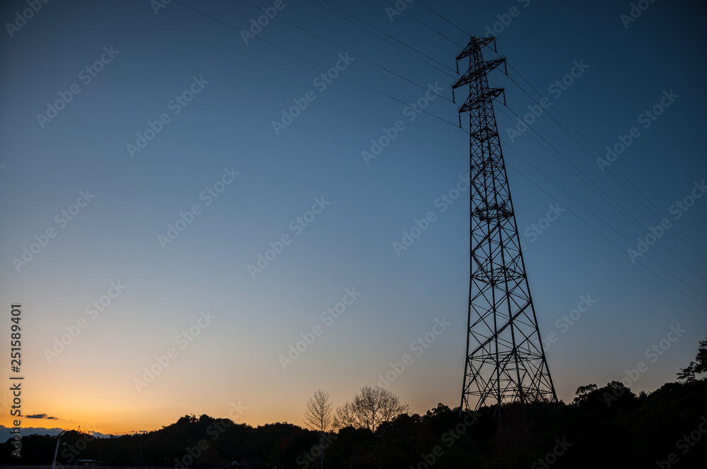 Silhouette of overhead power lines, tower and foreground with fading ...