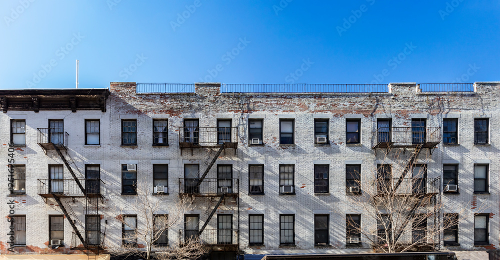 Old white brick apartment building with windows and fire escapes and an ...