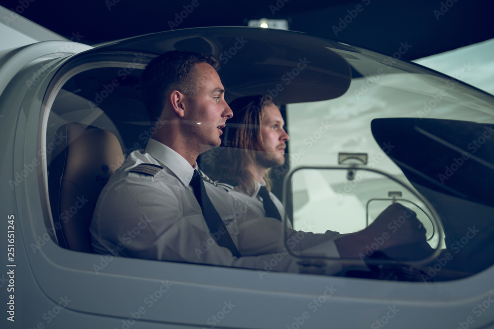 Side view of pilot with male trainee flying in flight simulator Stock ...