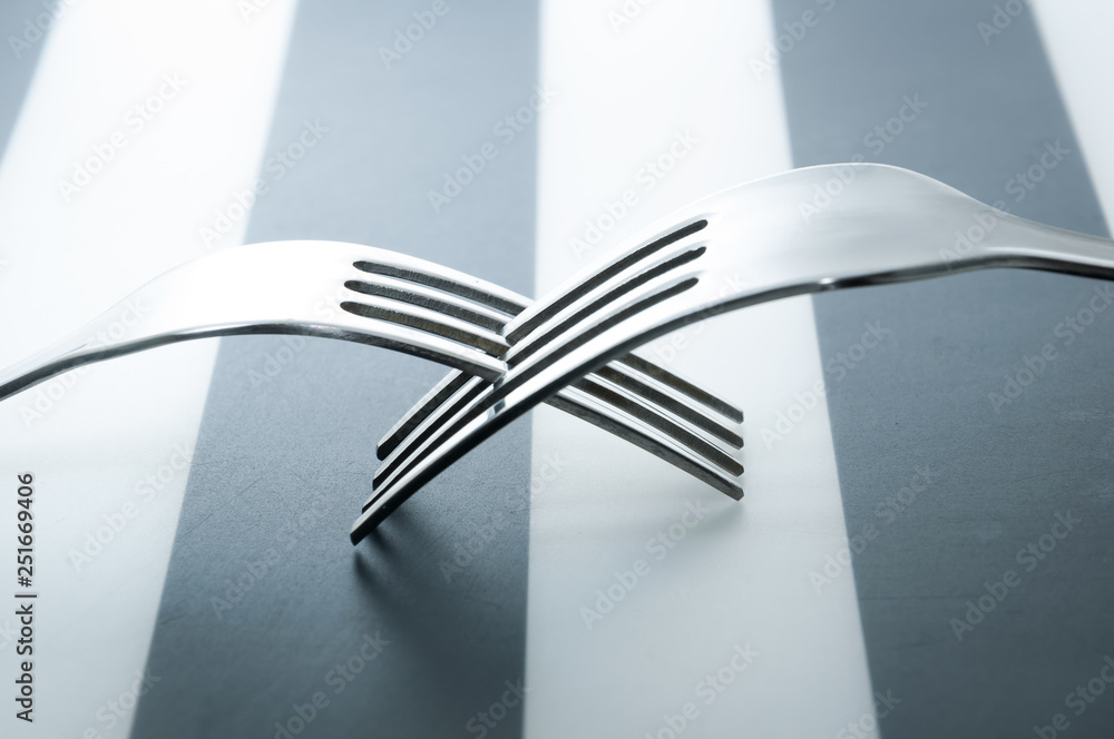 Two forks cross on striped background. 2 forks laying next to each ...