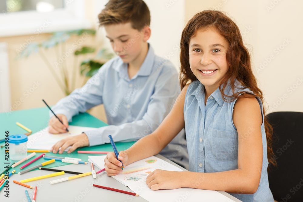 Handsome boy and red head girl drawing together in classroom with big ...