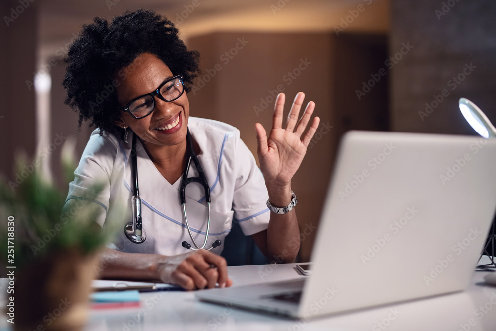 Happy African American doctor waving while making a video call over ...