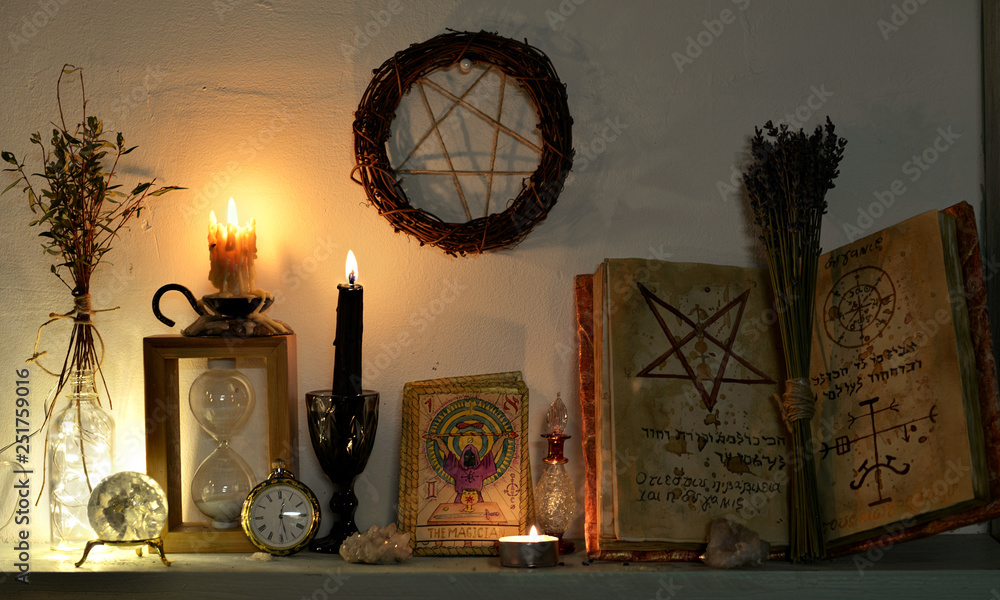 Open magic book with spells, tarot cards, crystals, candles and ...