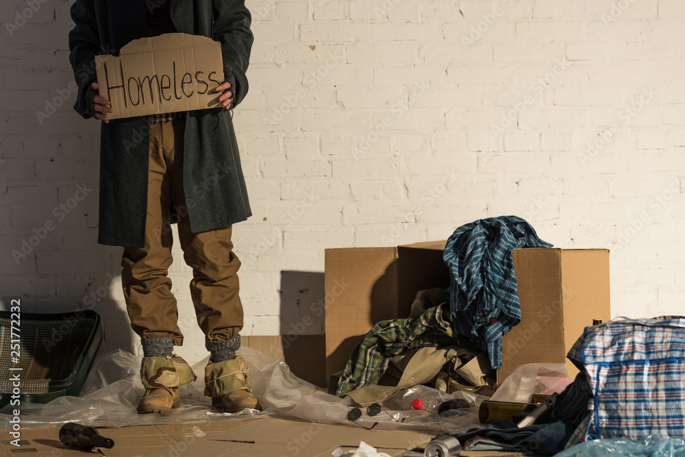 Foto de partial view of homeless man standing on garbage dump and ...