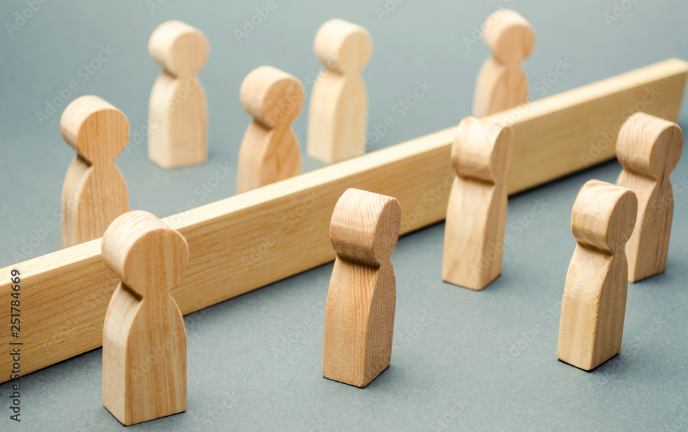 Wooden figures of people are separated by a barrier. Social classes ...