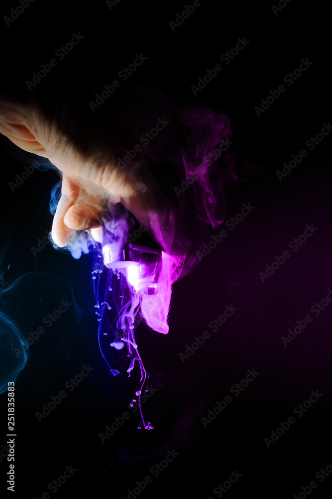 Male hand holds vape upside down. Vape clouds splash from coil on black ...