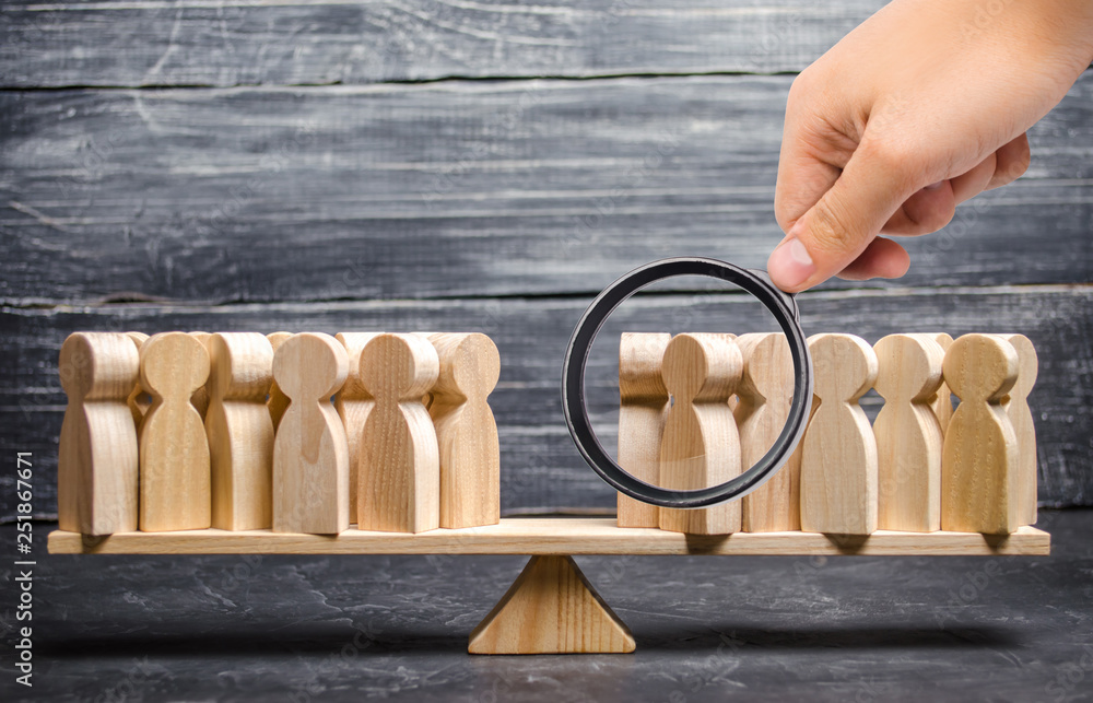 Magnifying glass is looking at the groups of people on the scales. The ...