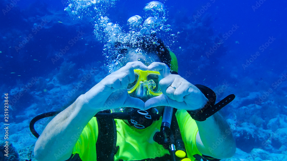 Scuba diving husband telling his wife that he loves her with heart ...