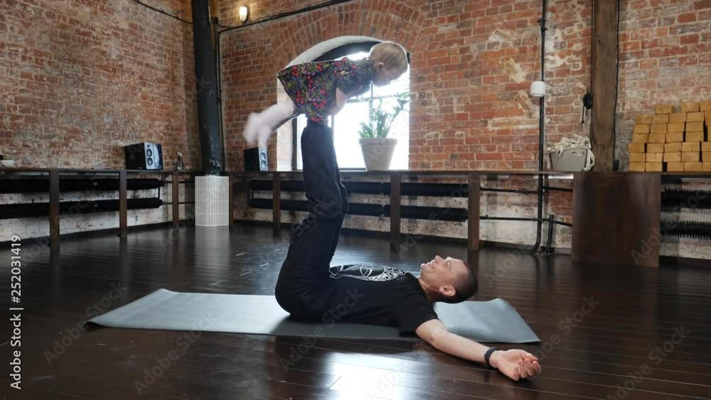 Acro yoga studio father practice a pose with his little child baby ...
