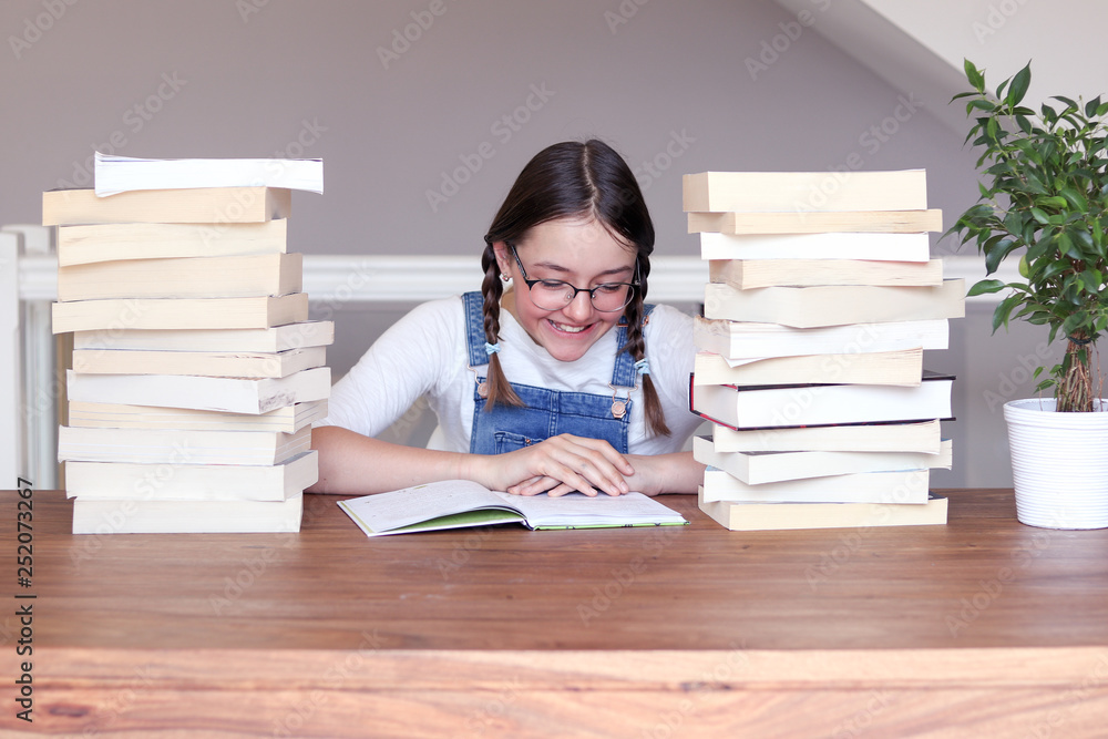 Cute happy smiling tween girl in glasses studying reading book sitting ...