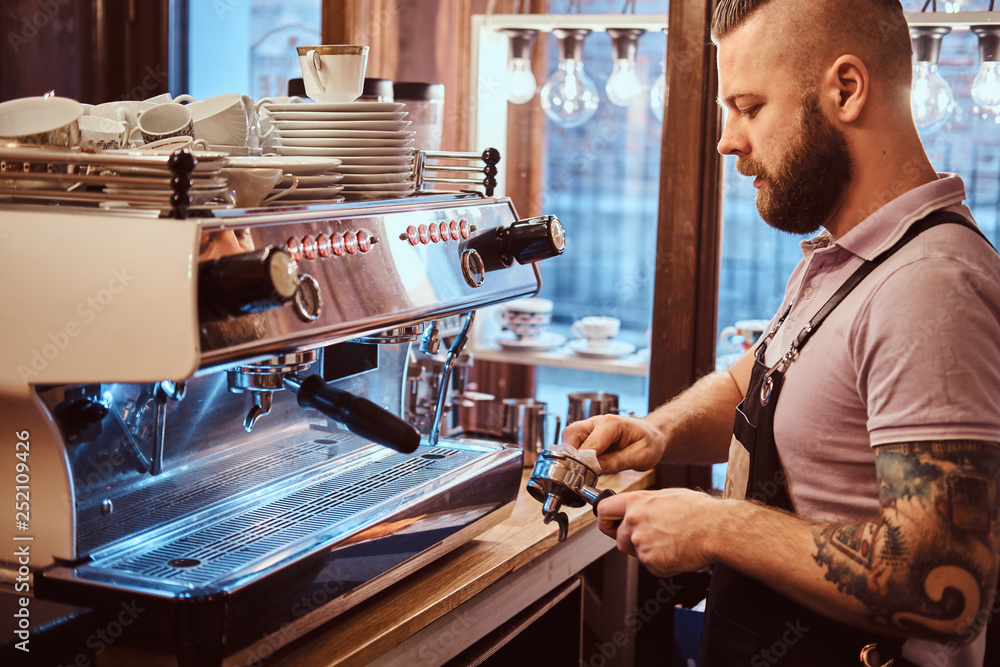 Side view of a barista cleans the portafilter before preparing the ...