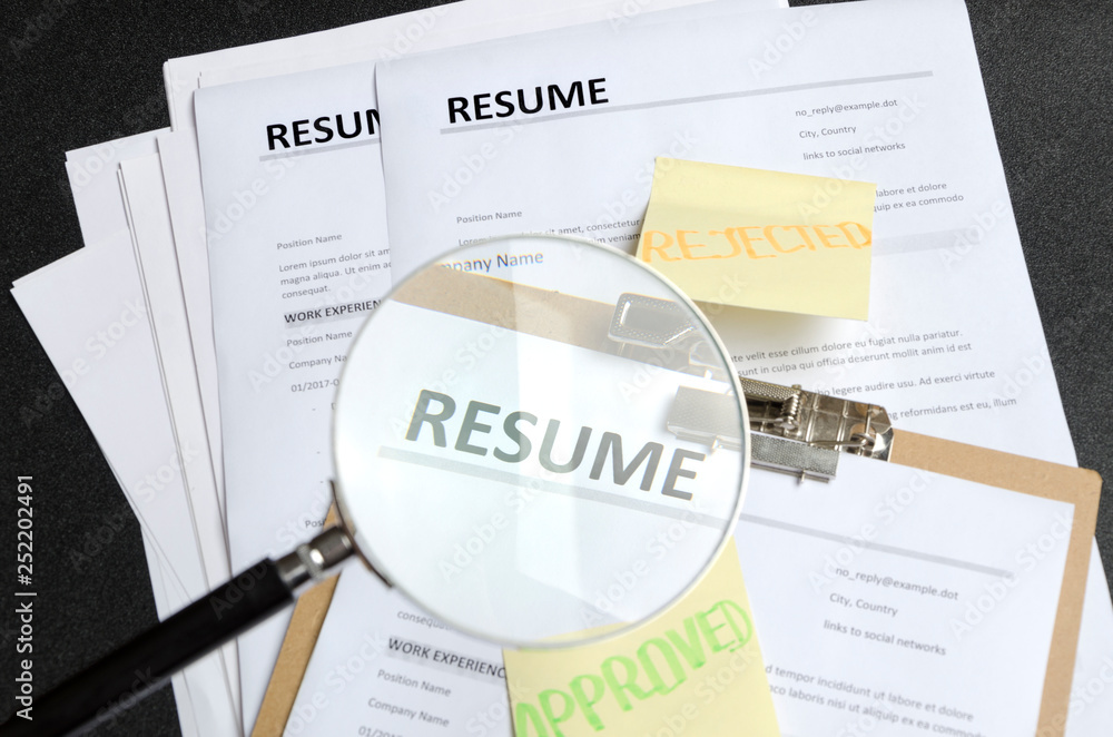 Pile of resume templates and sticks on it, black background. HR made ...
