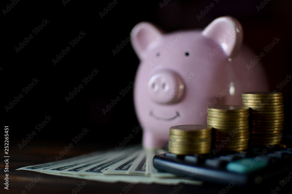 Pink piggy bank with coins banknote calculator on wood plank and black ...