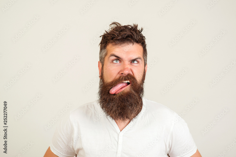 Crazy bearded man shows his tongue, on white background. Negative face ...