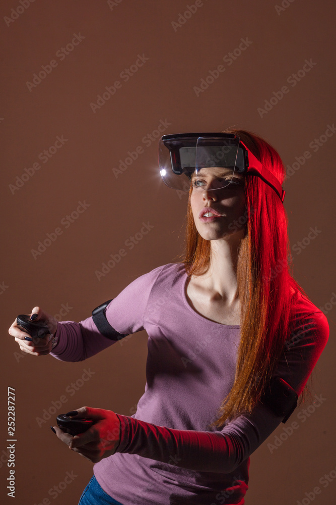 Young woman with long ginger hair sets programm for VR device to se 3 D ...