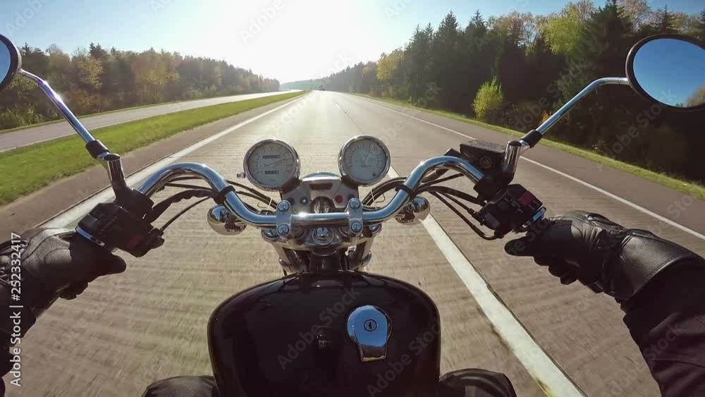 Fast motorcycle riding on highway towards sun, wide point of view of ...