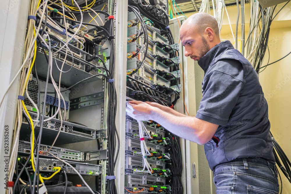 A specialist connects the wires in the server room of the data center ...