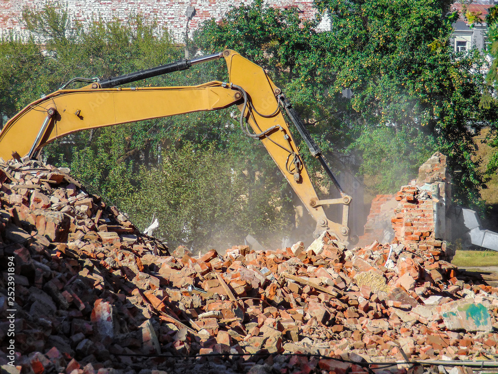 Dismantling a brick building with a bucket excavator. Ruins and remains ...